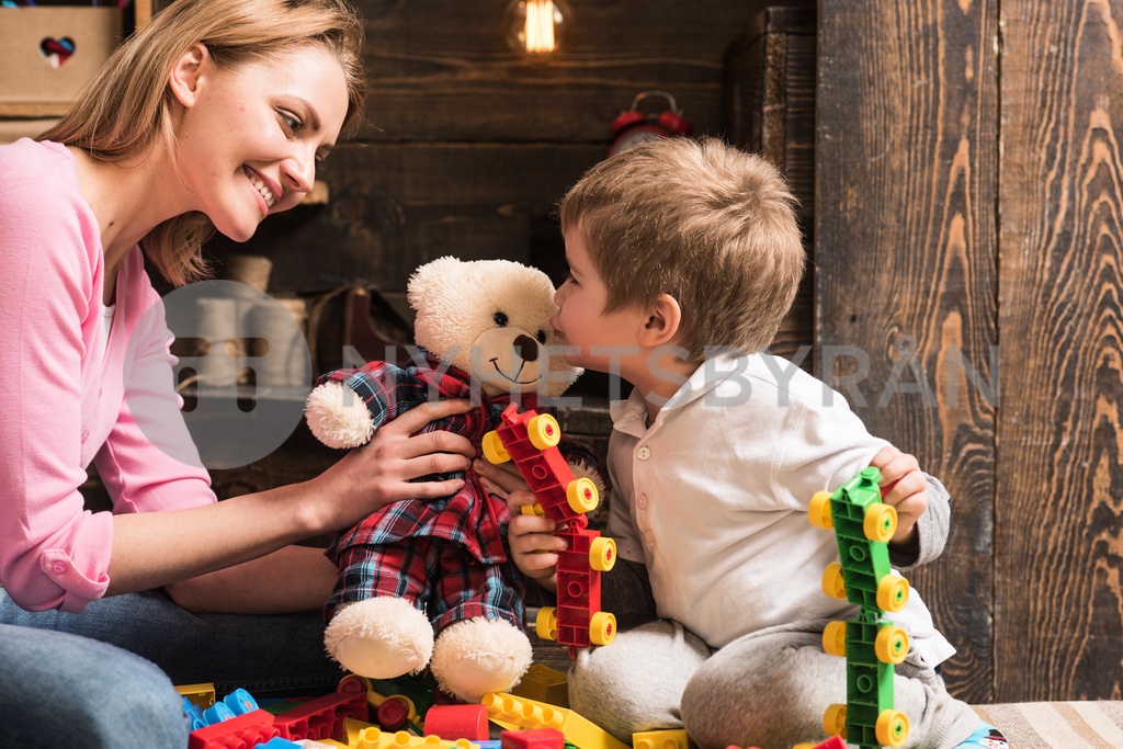 Closeup smiling mom and kid playing with teddy. Cute little boy kissing ...
