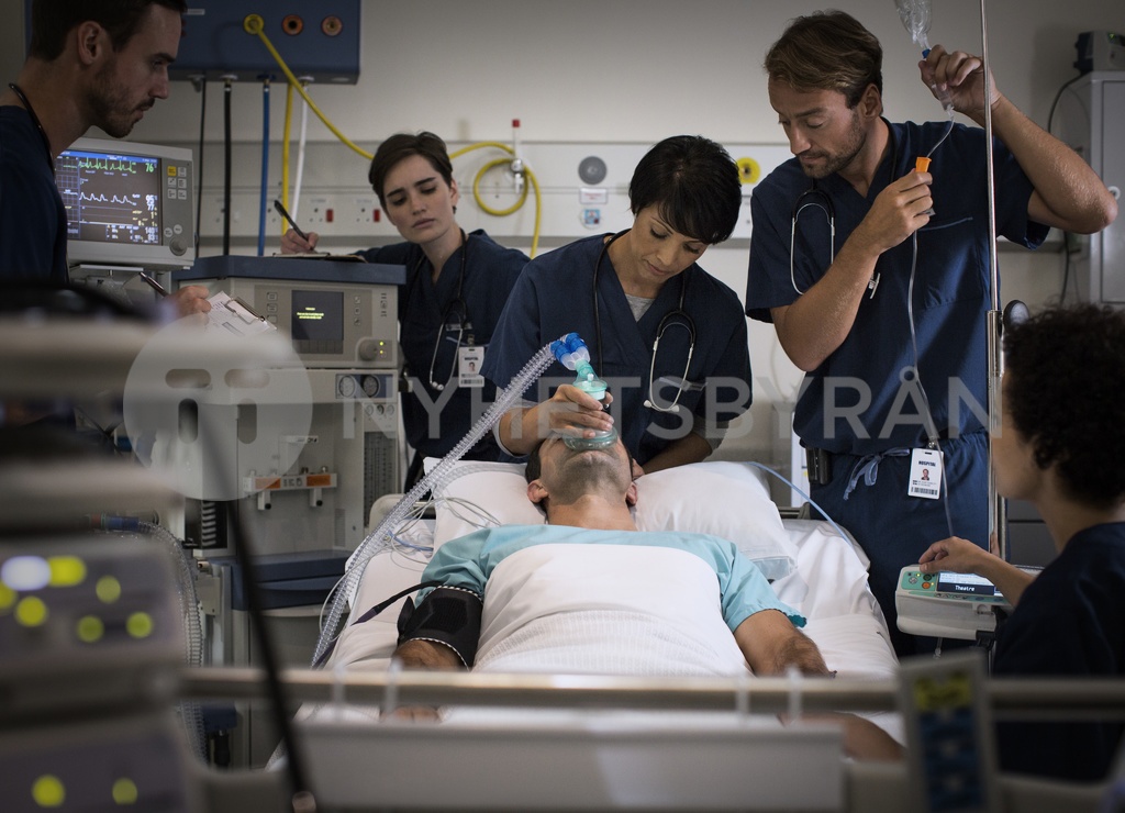 Doctor holding mask over patient's mouth and doctor controlling IV drip ...