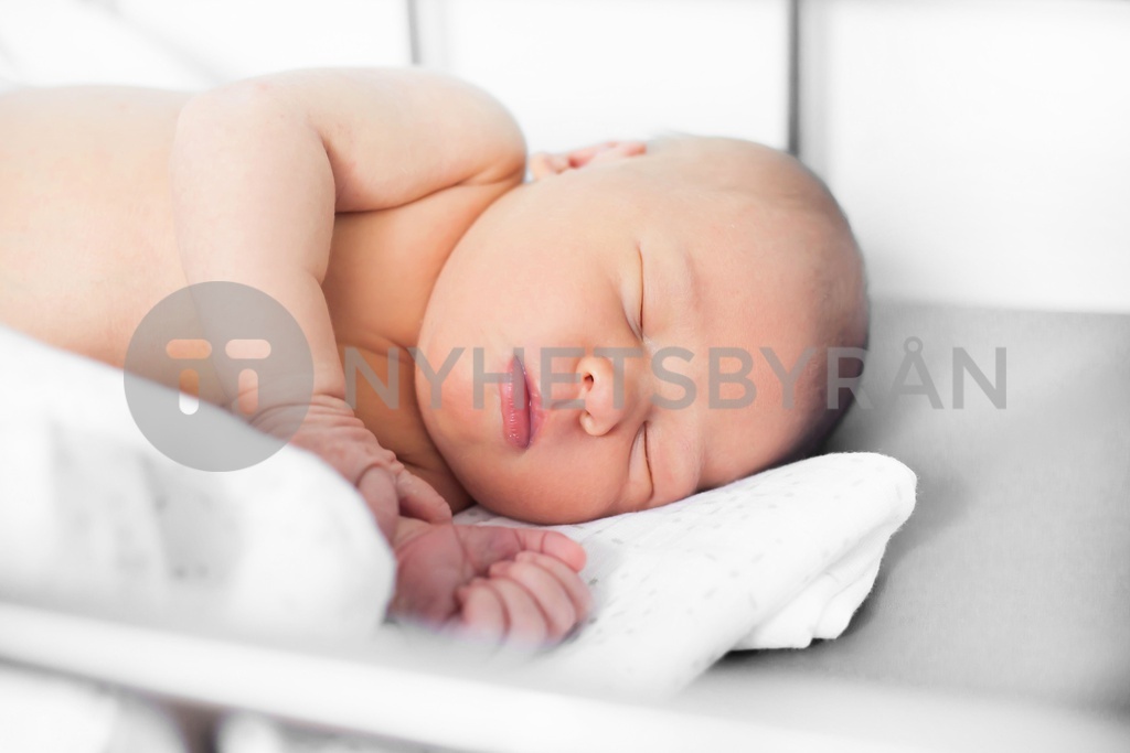 pretty newborn baby with tag on hand